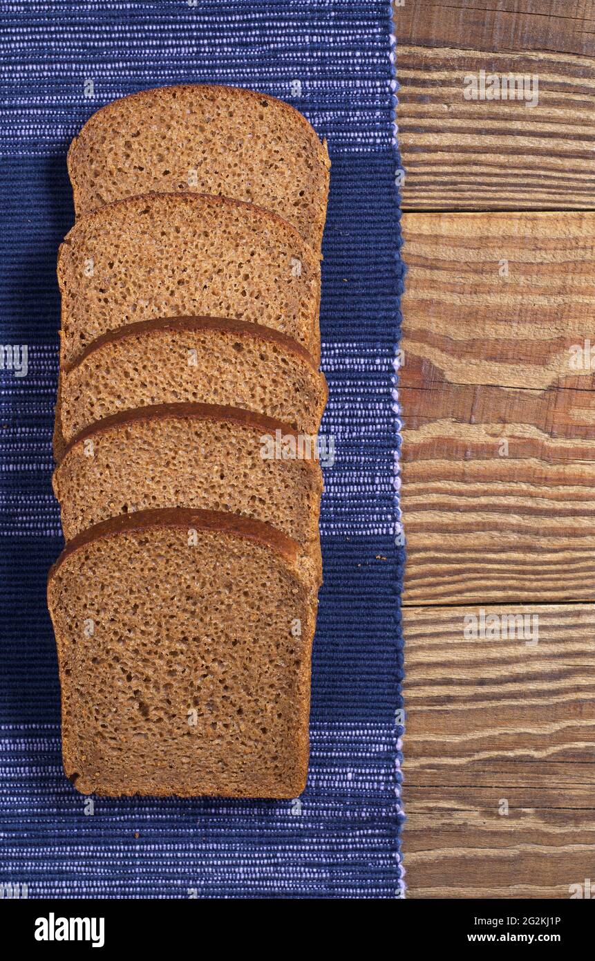 Black rye bread sliced on wooden table with blue tablecloth, top view Stock Photo - Alamy