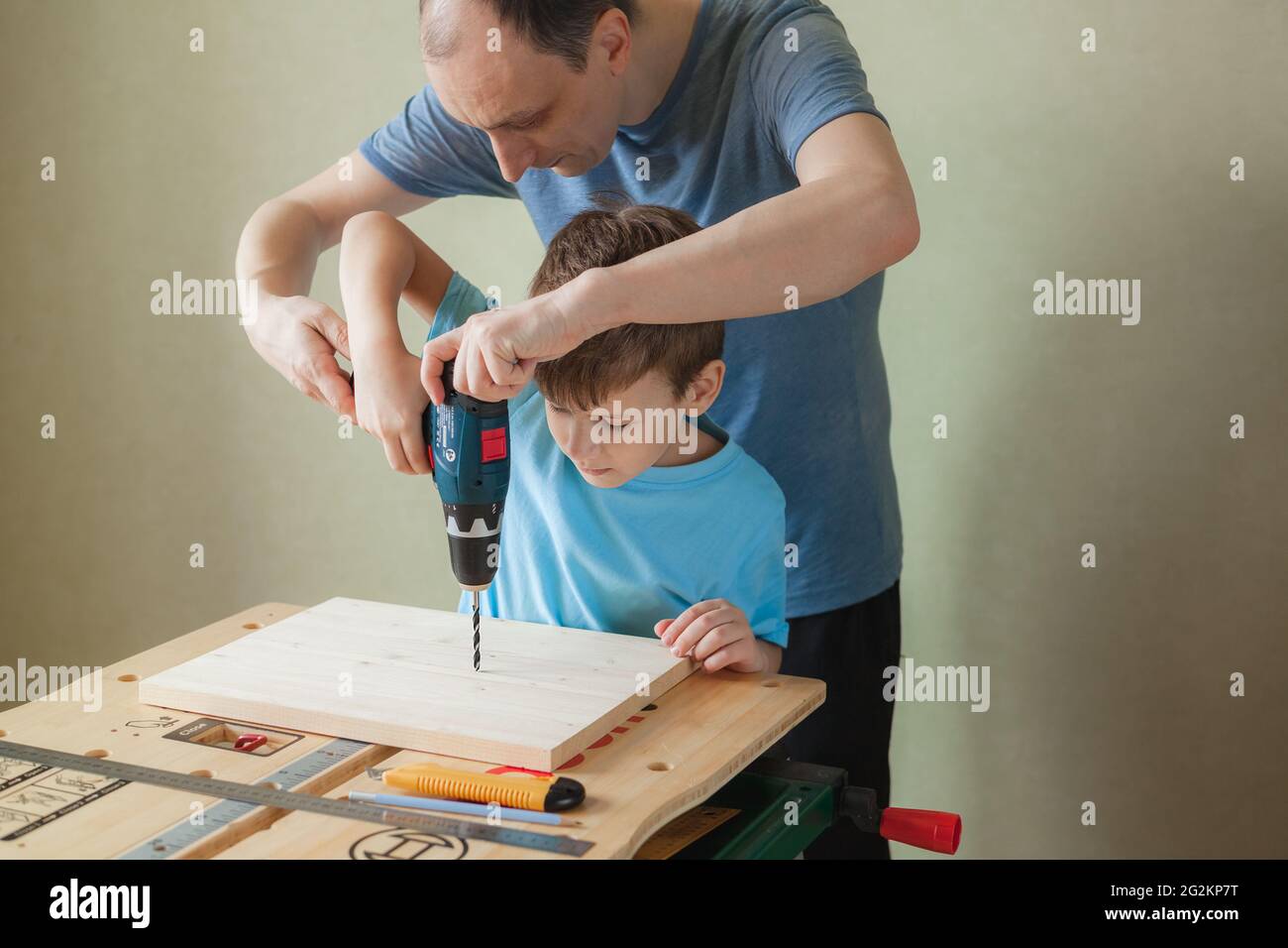 Dad and son work together while standing at workbench. Little boy ...