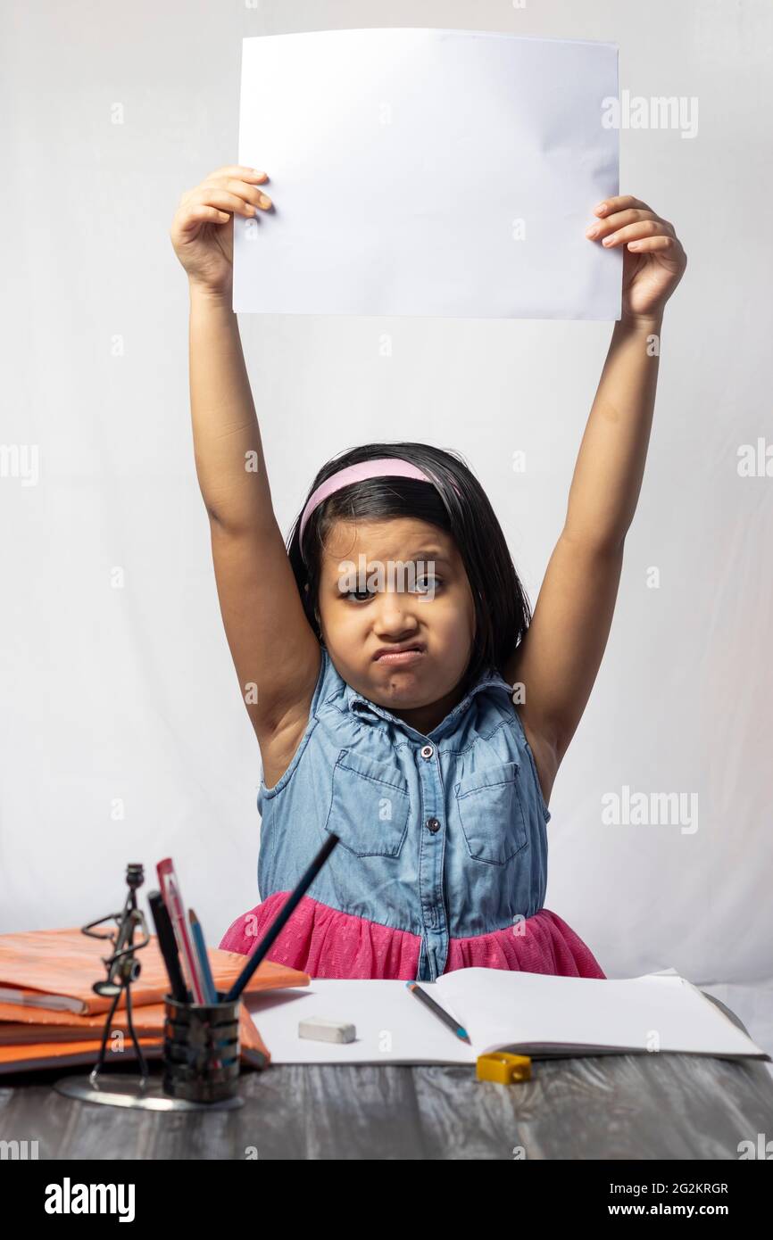 A unhappy Indian girl child holding a blank sheet of paper over her ...