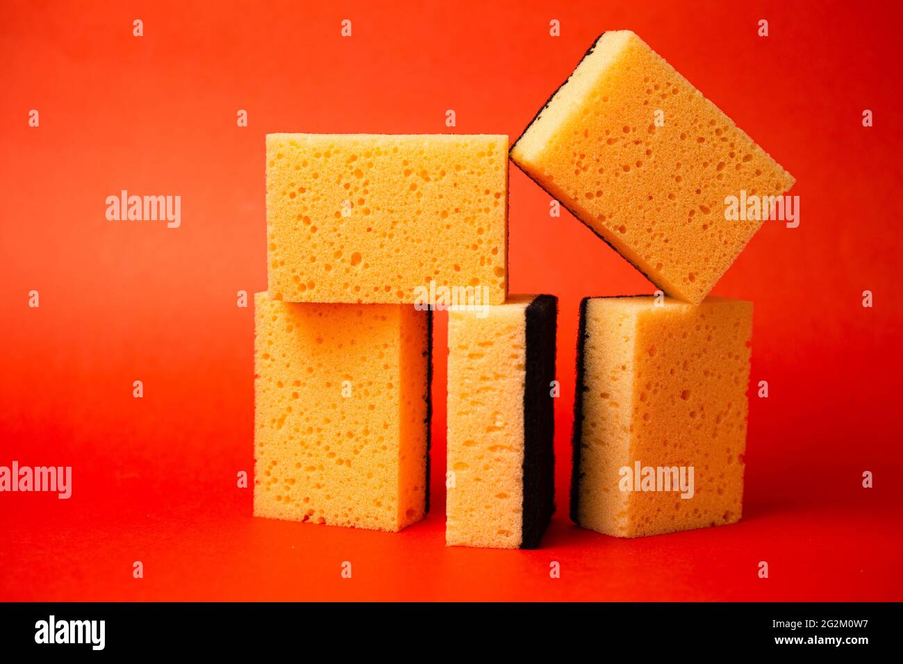five sponges for cleaning on a red background Stock Photo - Alamy