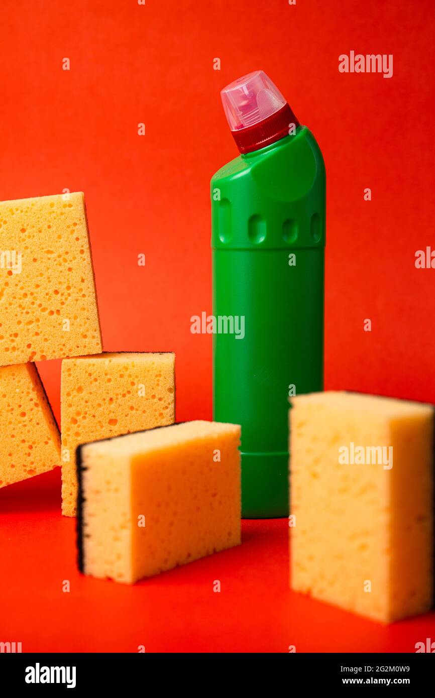 A bottle of detergent with cleaning sponges on a red background Stock ...