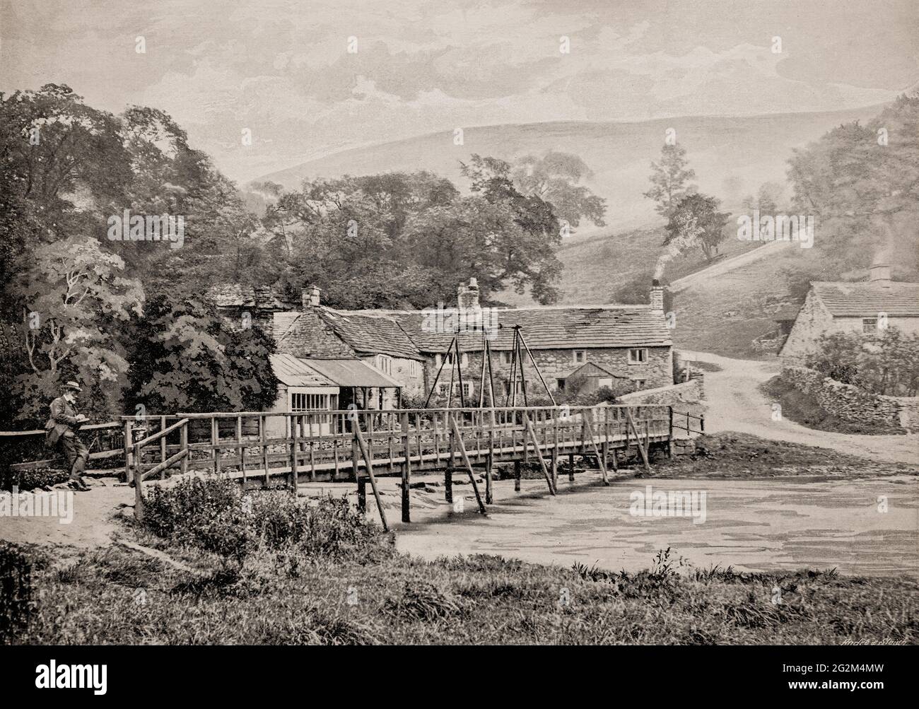A late 19th century view of cottages near an old footbridge across the ...