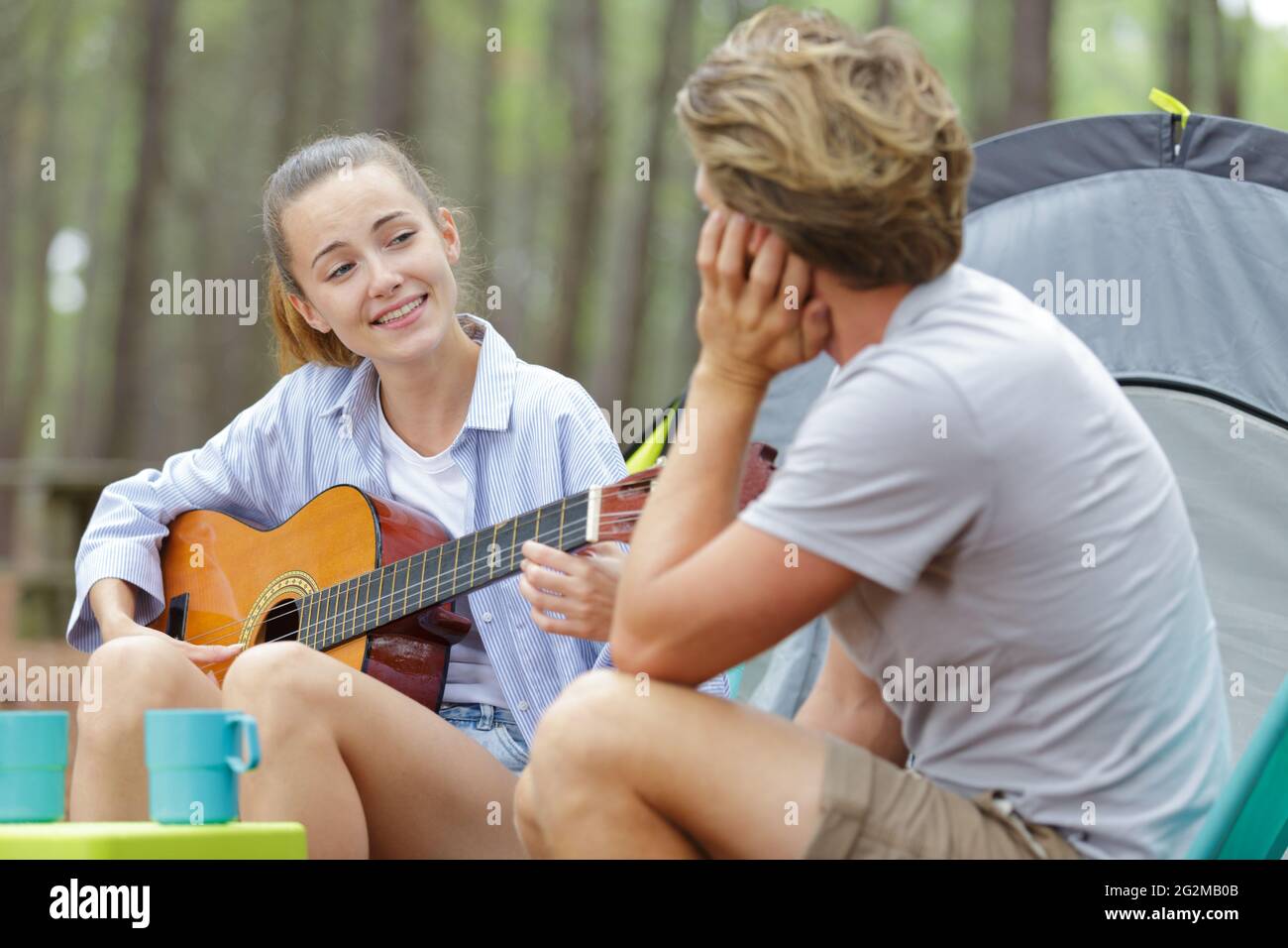 woman singing to boyfriend in a camp site Stock Photo - Alamy