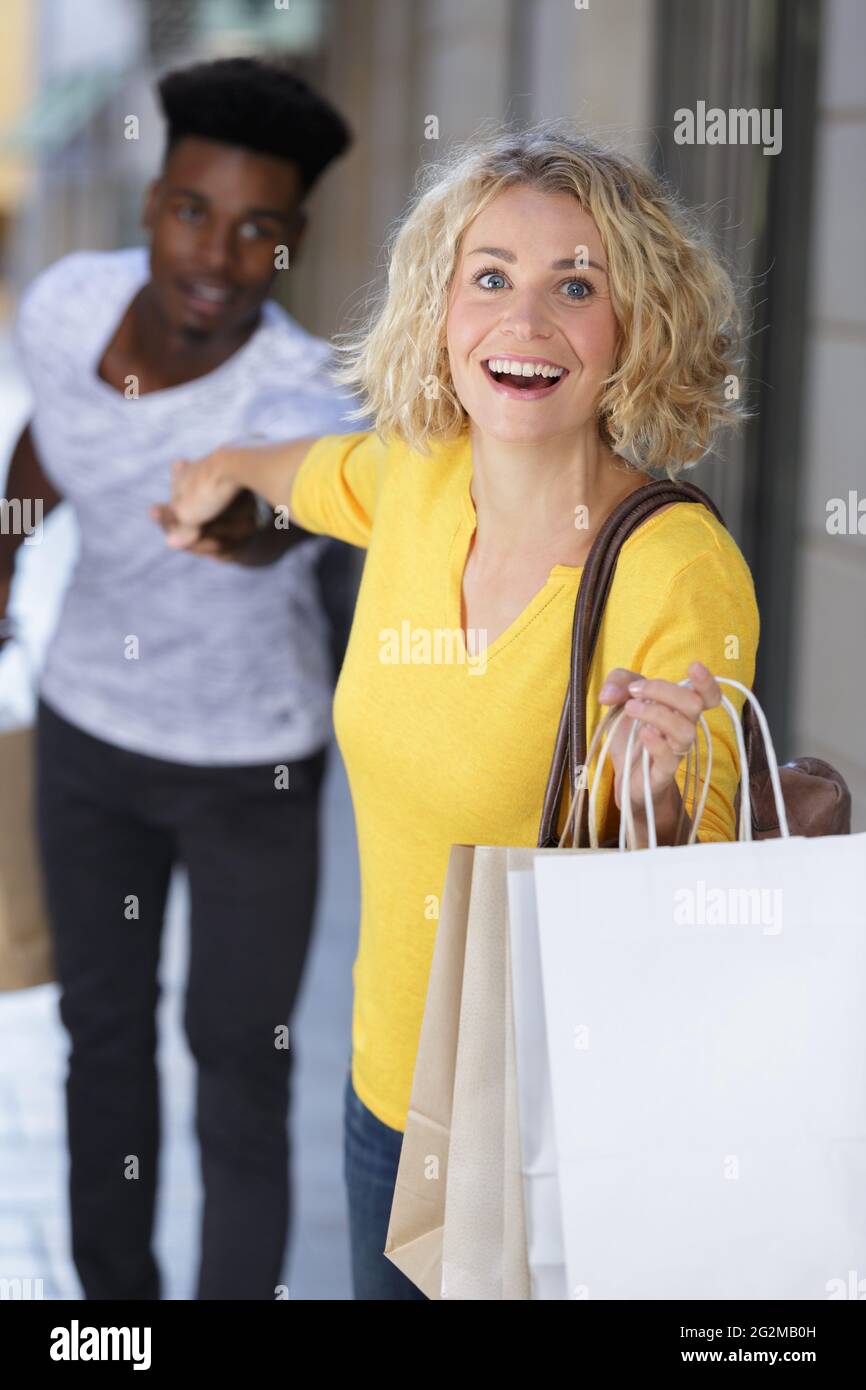 woman dragging man into shopping mall Stock Photo - Alamy
