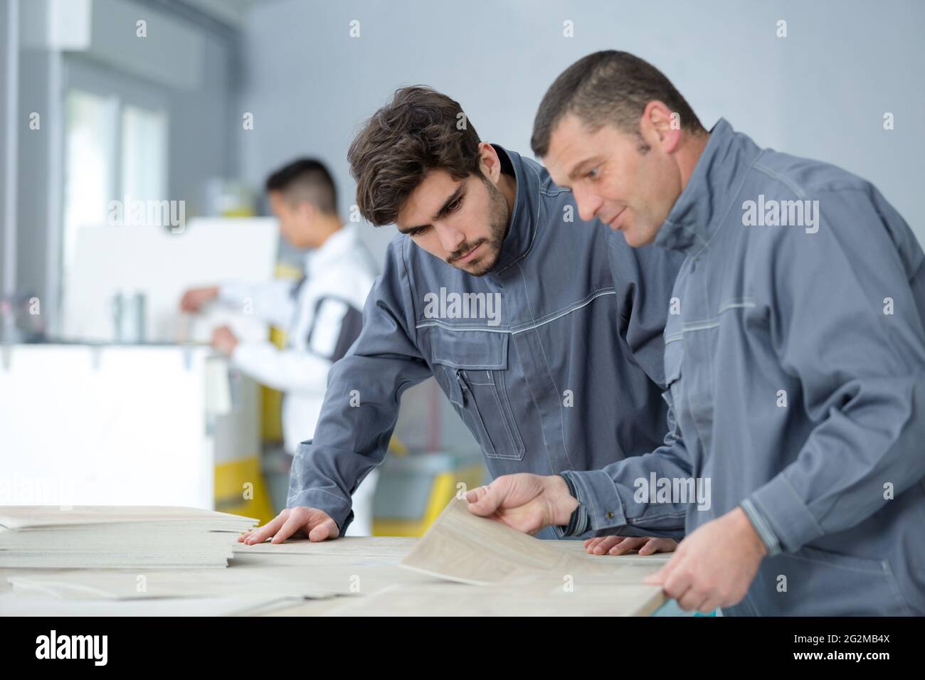 supervisor holding paperwork with workers in factory Stock Photo - Alamy