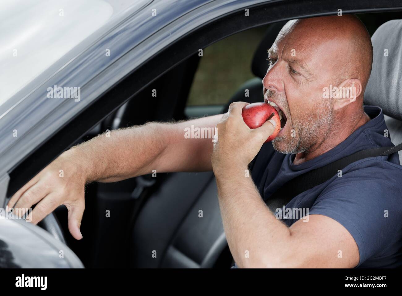 man eating an apple driving his car Stock Photo - Alamy