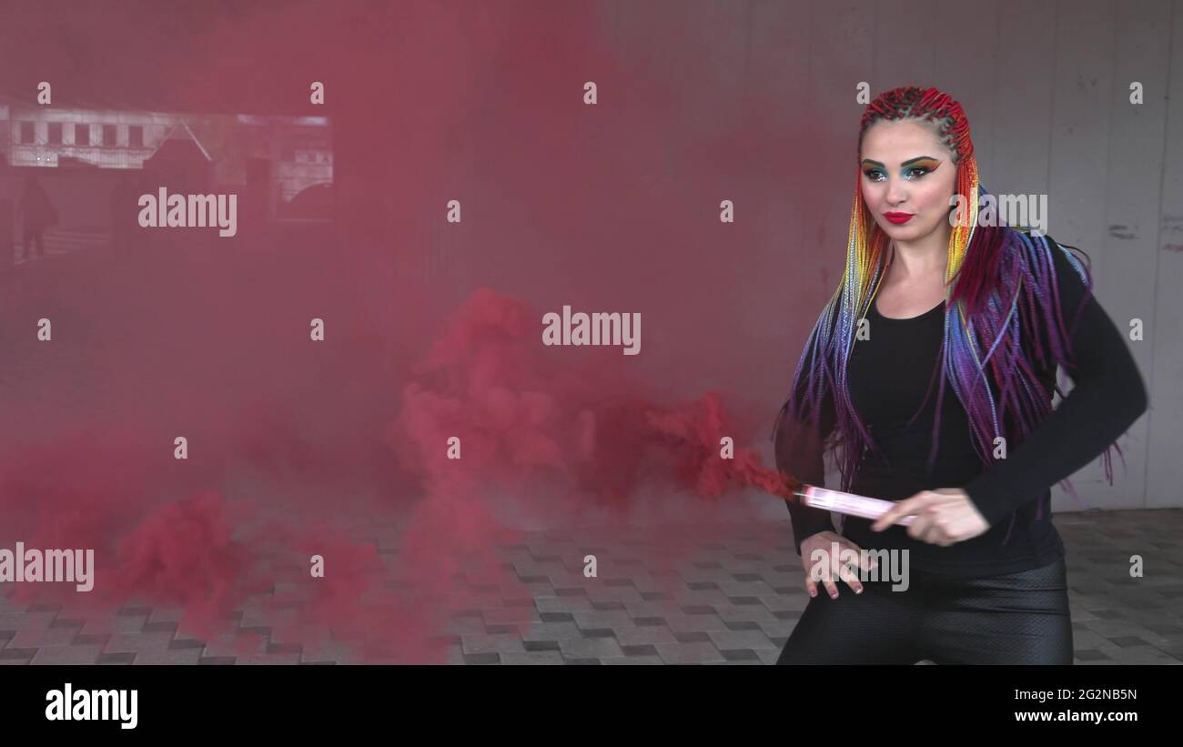 Attractive girl with multicolored braids and makeup in an black dress ...