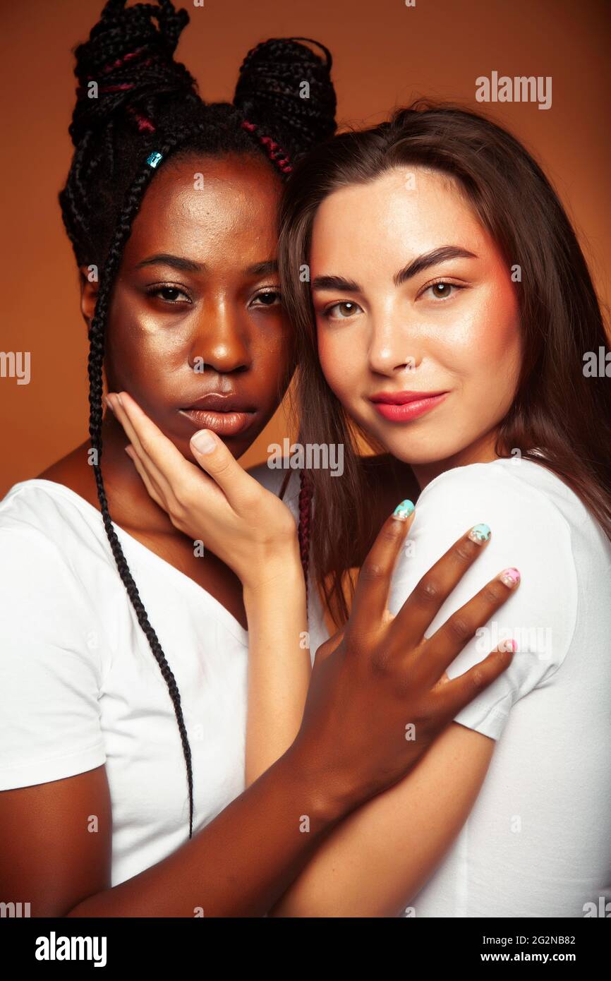 young pretty asian, afro woman posing cheerful together on brown ...