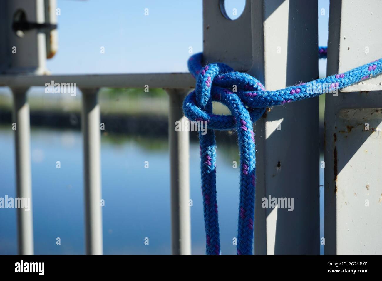 Closeup of a rope tied in a knot outdoors near a body of water during ...