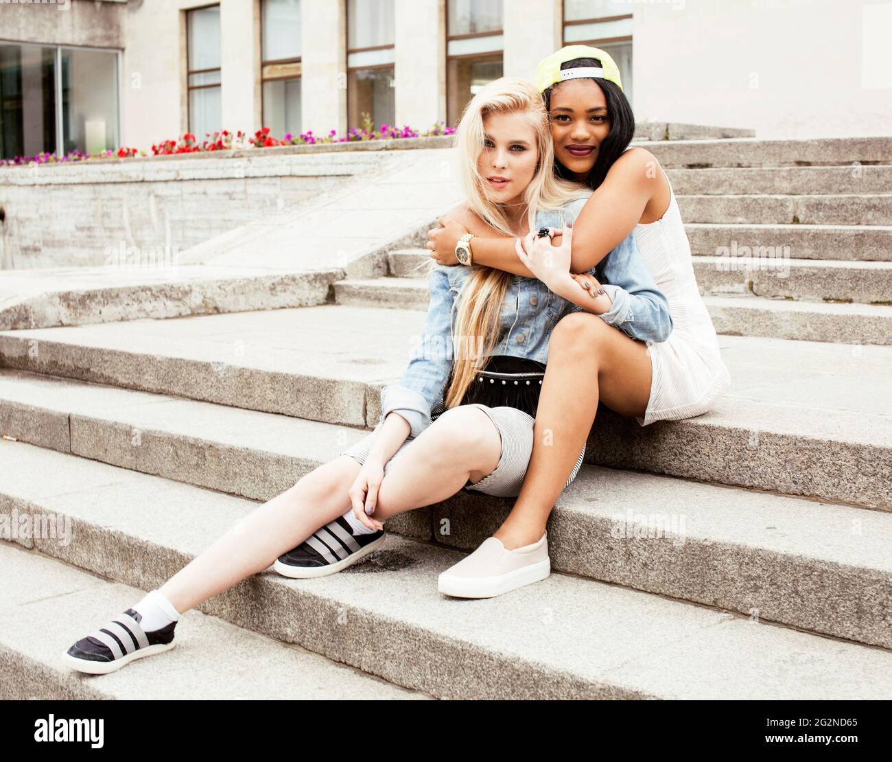 Two teenage girls infront of university building smiling, having fun ...