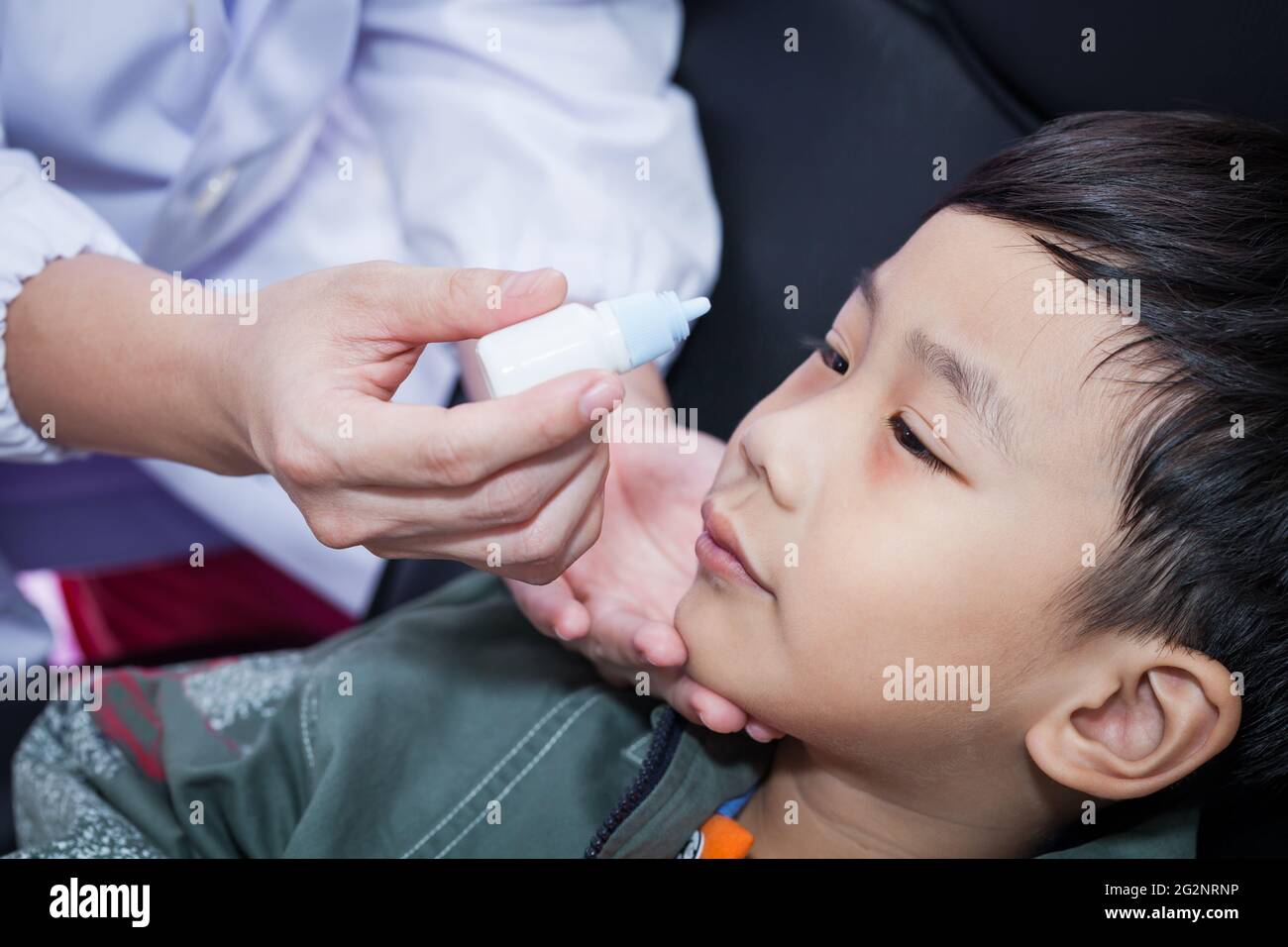 Doctor pouring eye drops in eye patient (conjunctivitis). Studio shot ...