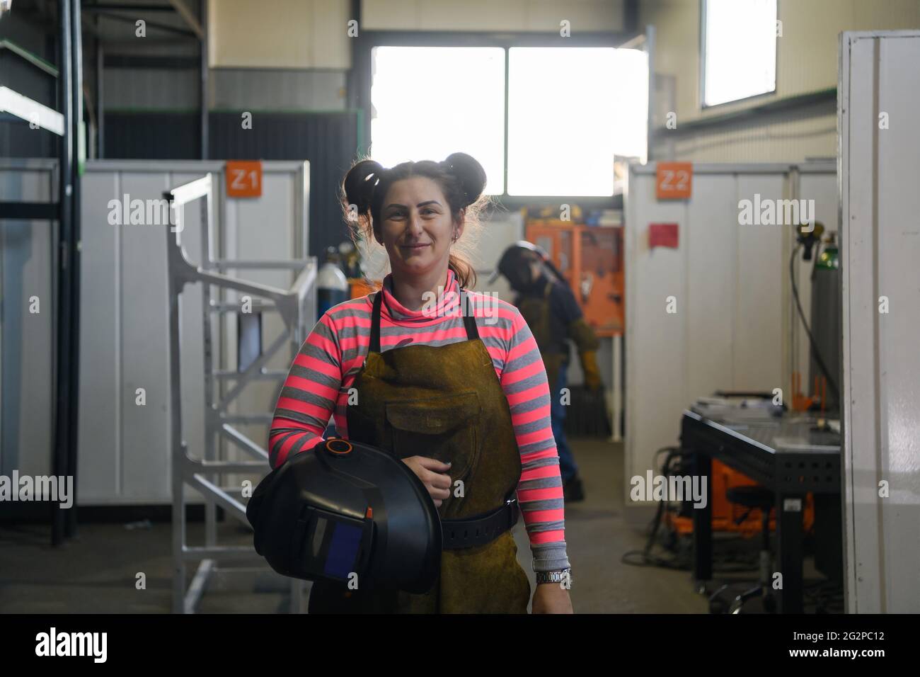 a portrait of a women welder holding a helmet and preparing for a ...