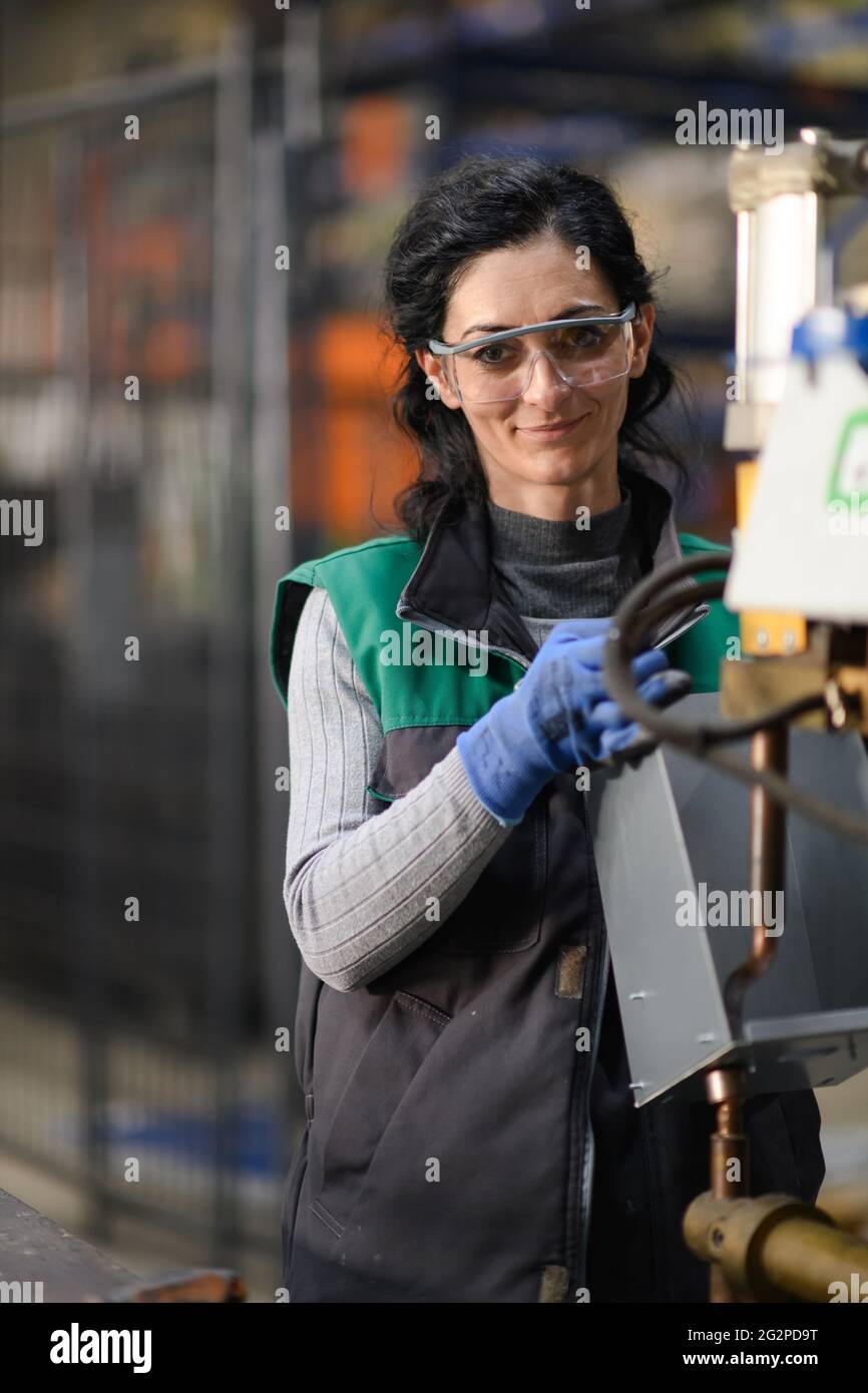 Woman worker wearing safety goggles control lathe machine to drill ...
