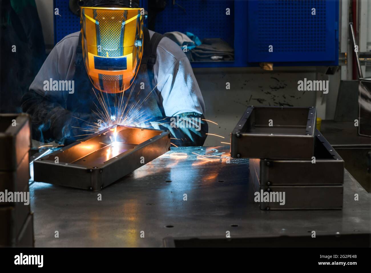 Professional welder performs work with metal parts in factory, sparks ...