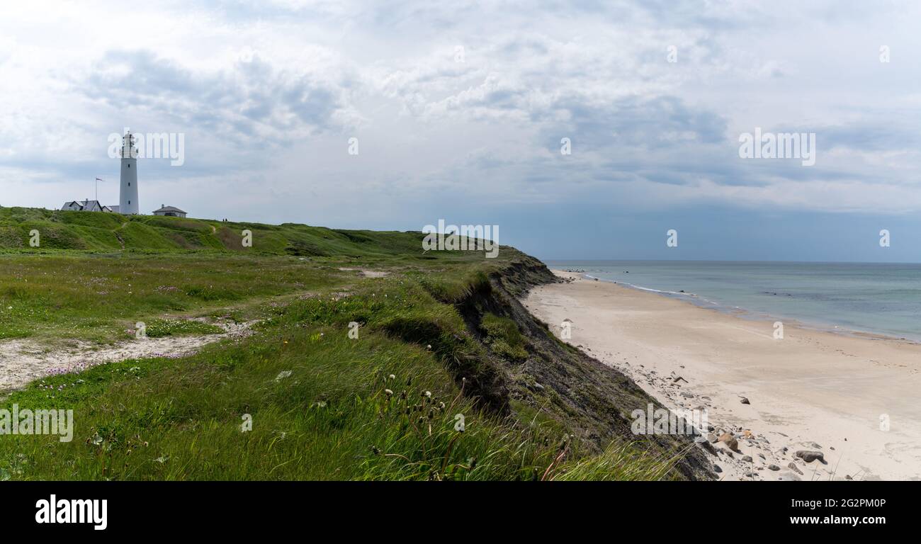A panorama of the lighthouse and grassy sand dunes above the white sand ...
