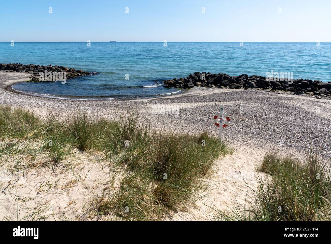 A beautiful empty beach behind sand dunes with rocky storm groins to ...
