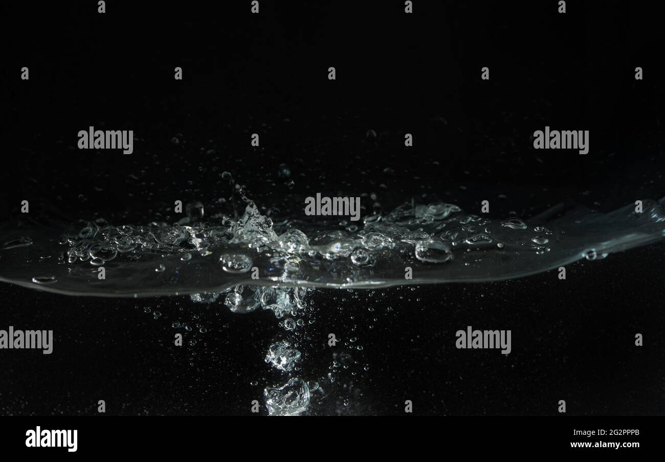Water splashing as it's poured into aquarium tank, black background ...