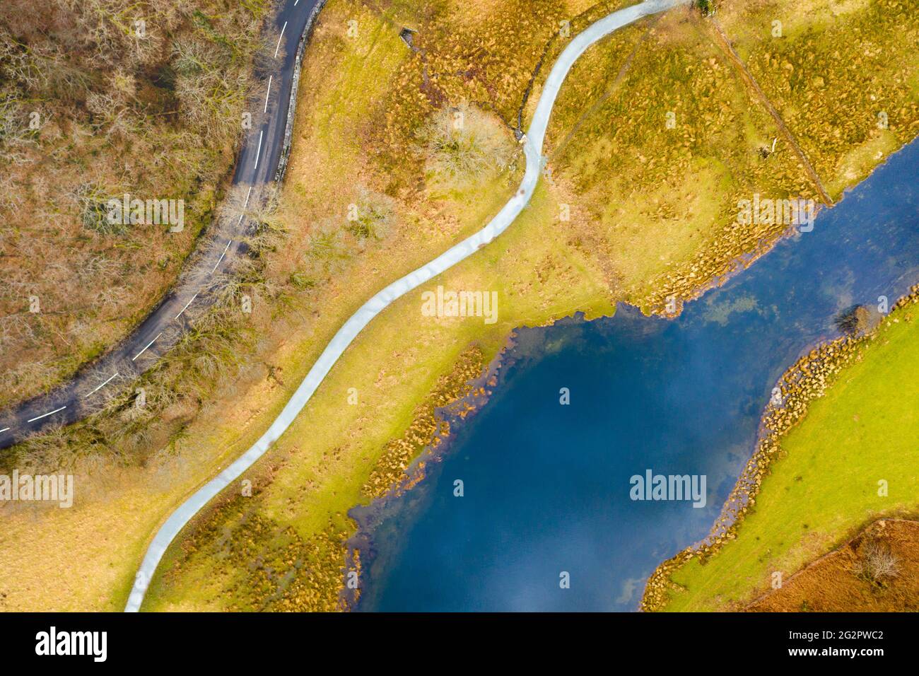 Aerial birds eye view of river, footpath and winding asphalt road in ...
