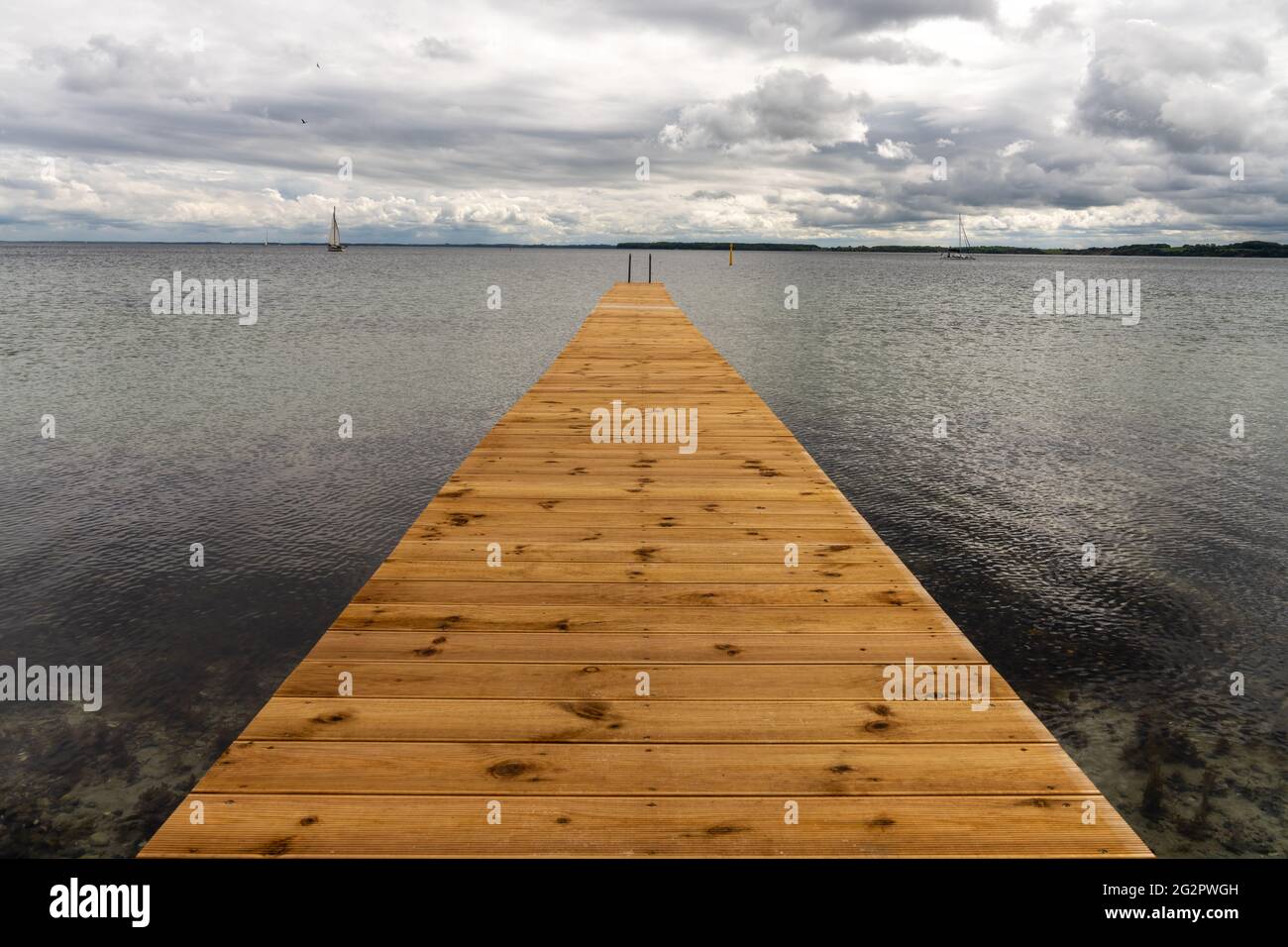 A view of a long wooden pier leading out into clear ocean waters with ...