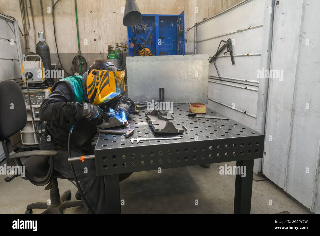 Professional welder performs work with metal parts in factory, sparks ...