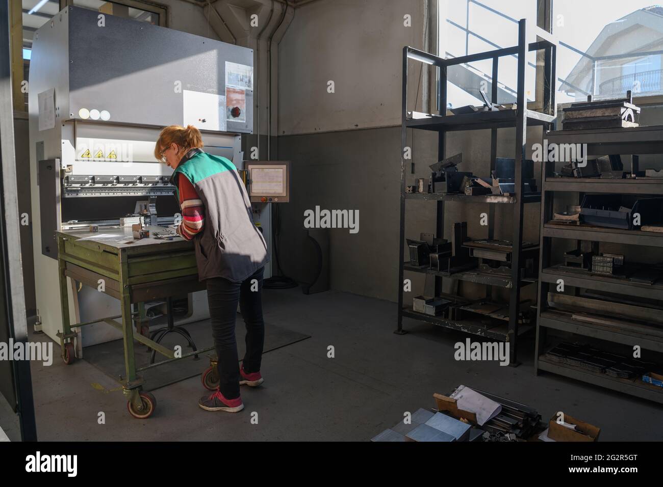 woman working in a modern factory and preparing materia for a CNC ...