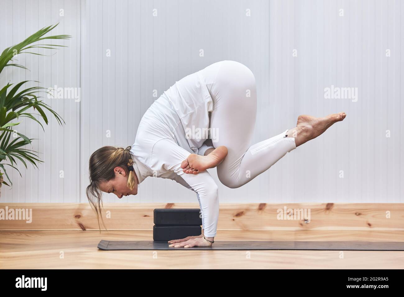 Athletic woman doing the advanced yoga posture Crow pose, kakasana ...