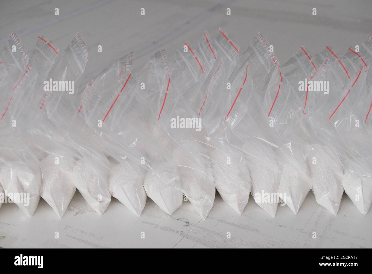 A large number of transparent sachets filled with white powder. White ...