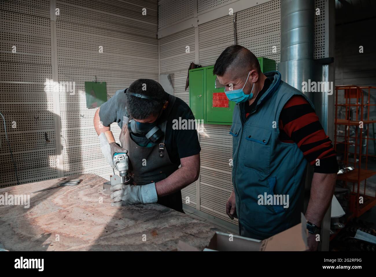 Industrial work during a pandemic. Two men work in a heavy metal ...