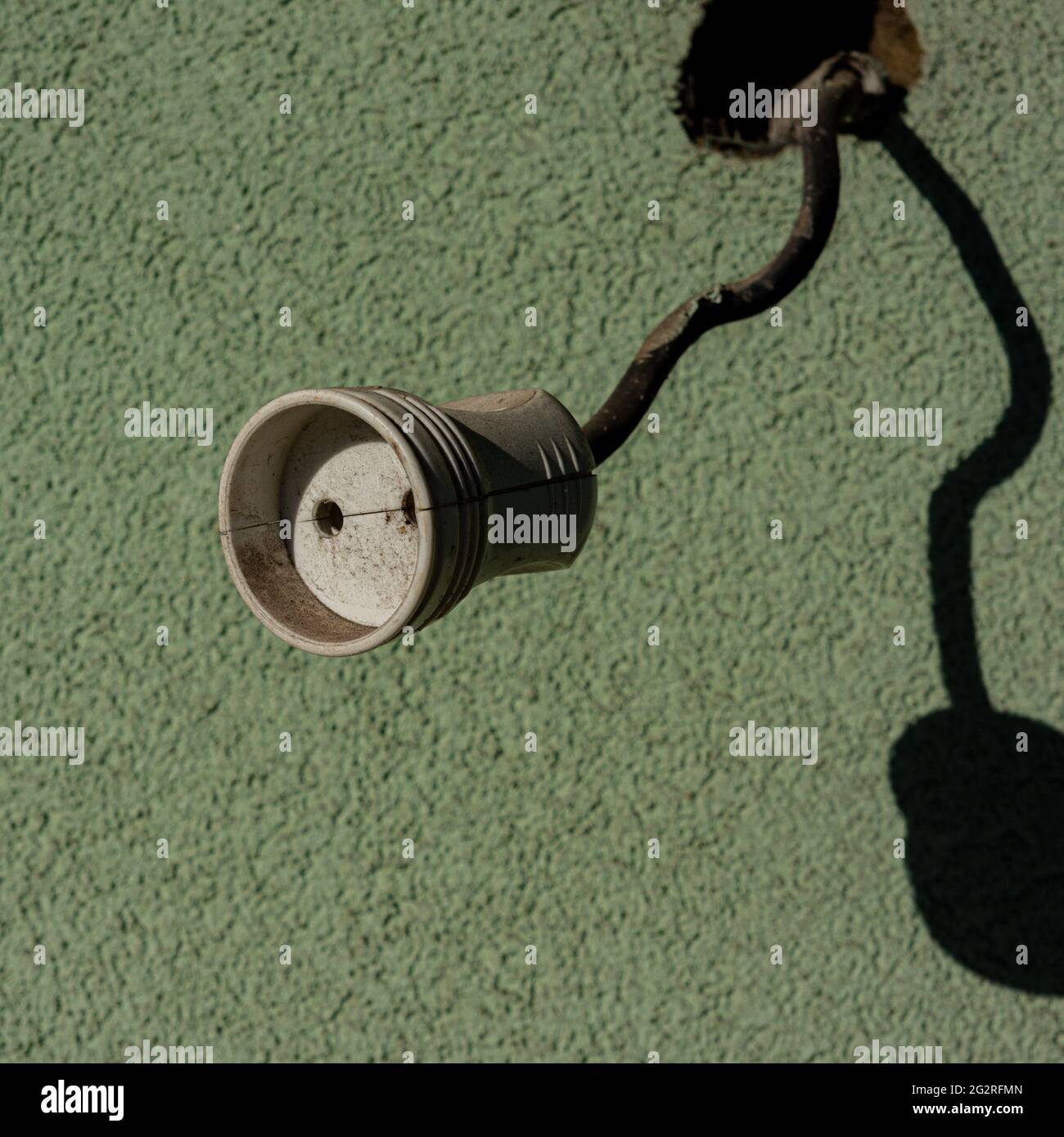 Electrical outlet on a wire sticking out of the wall and a shadow ...