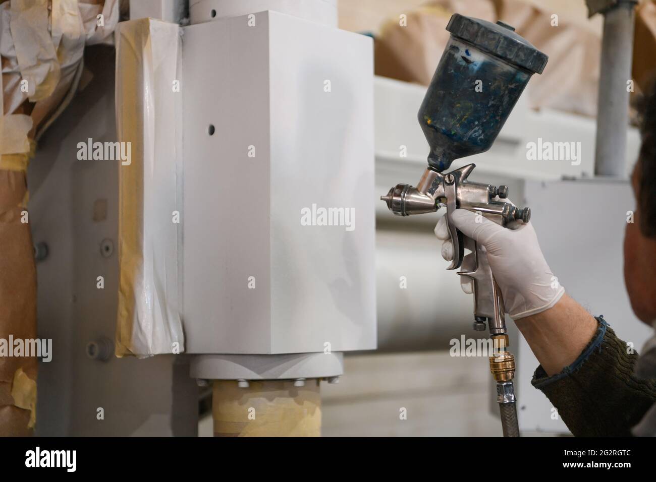 A worker painting to mechanical part with airless spray Stock Photo - Alamy