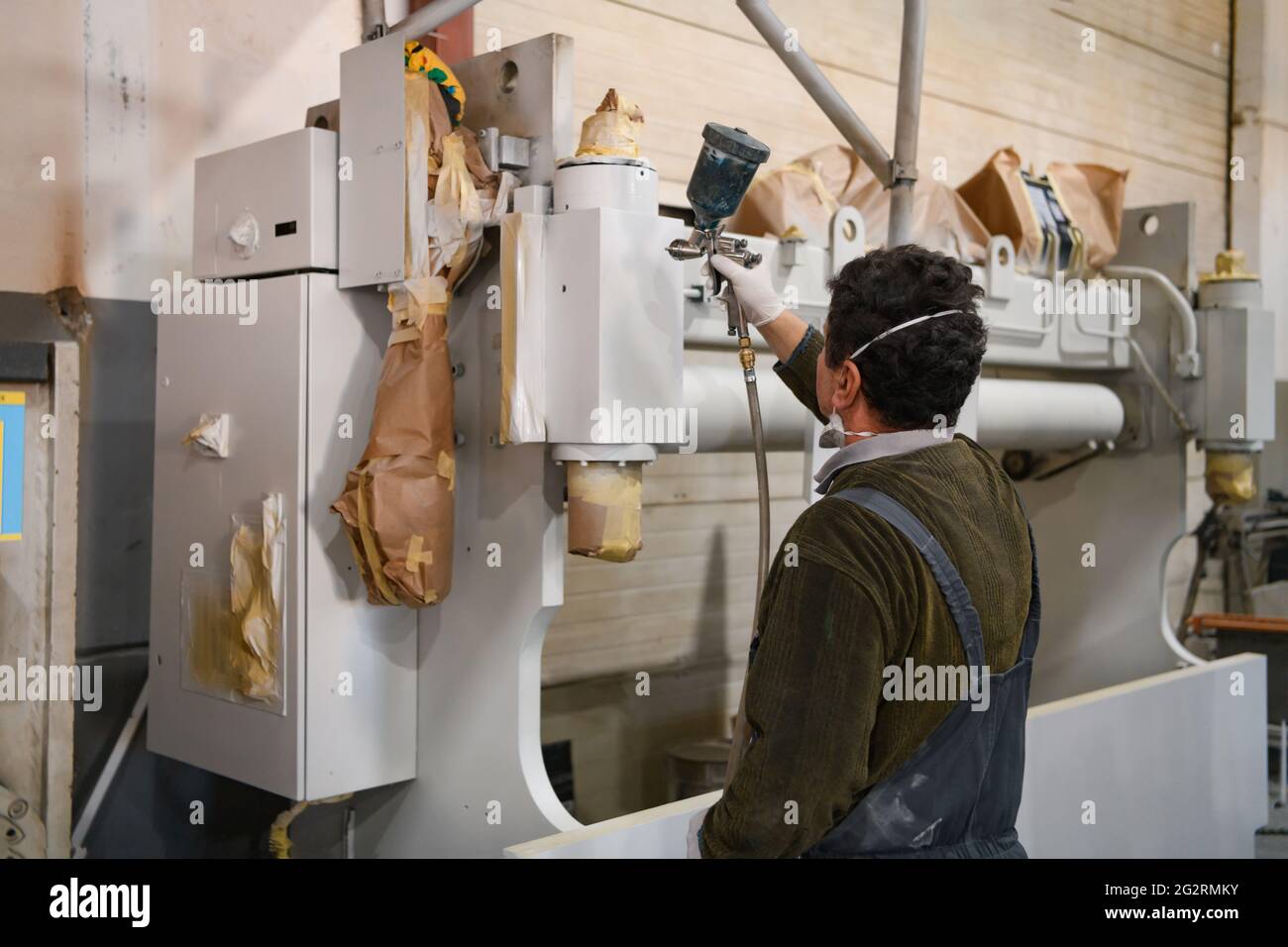 A worker painting to mechanical part with airless spray Stock Photo - Alamy