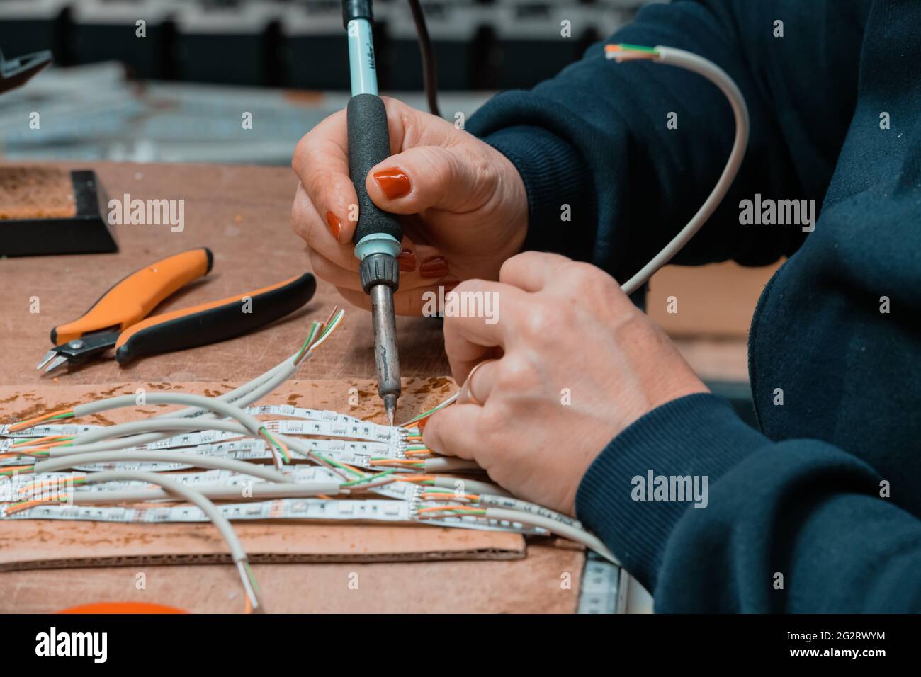 Industrial worker woman soldering cables of manufacturing equipment in ...