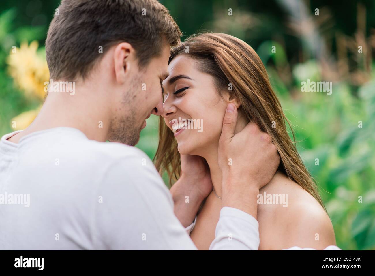 Loving couple in white dresses kissing, smiling, hughing in field of ...