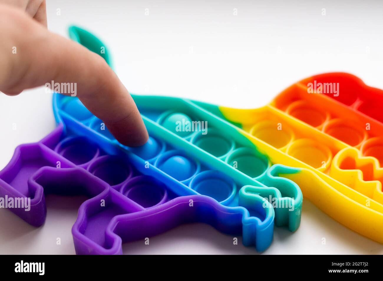 Popit rainbow toy in rainbow colours and dino shape. Trendy bubble pop ...