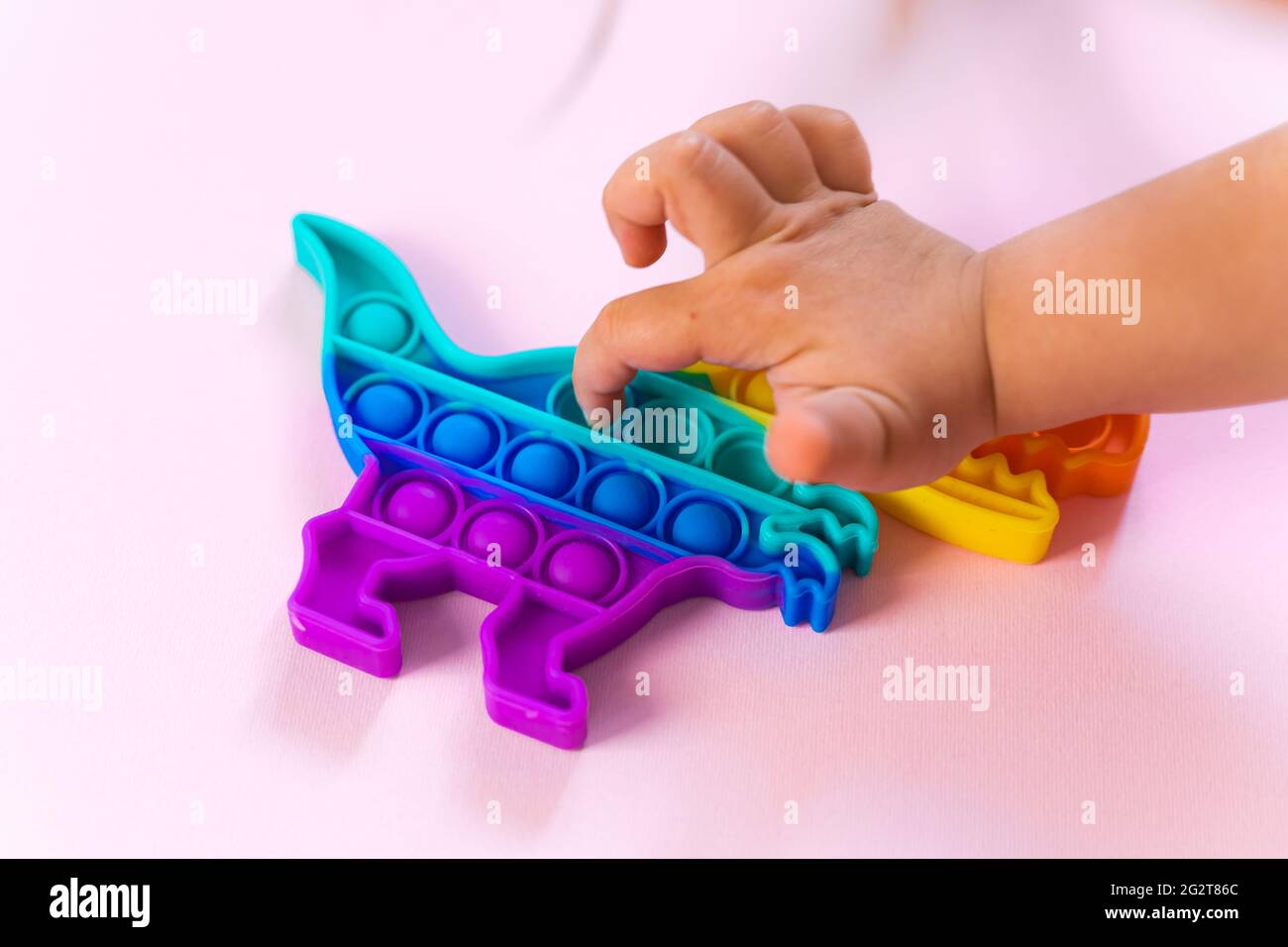 Popit rainbow toy in rainbow colours and dino shape. Trendy bubble pop ...