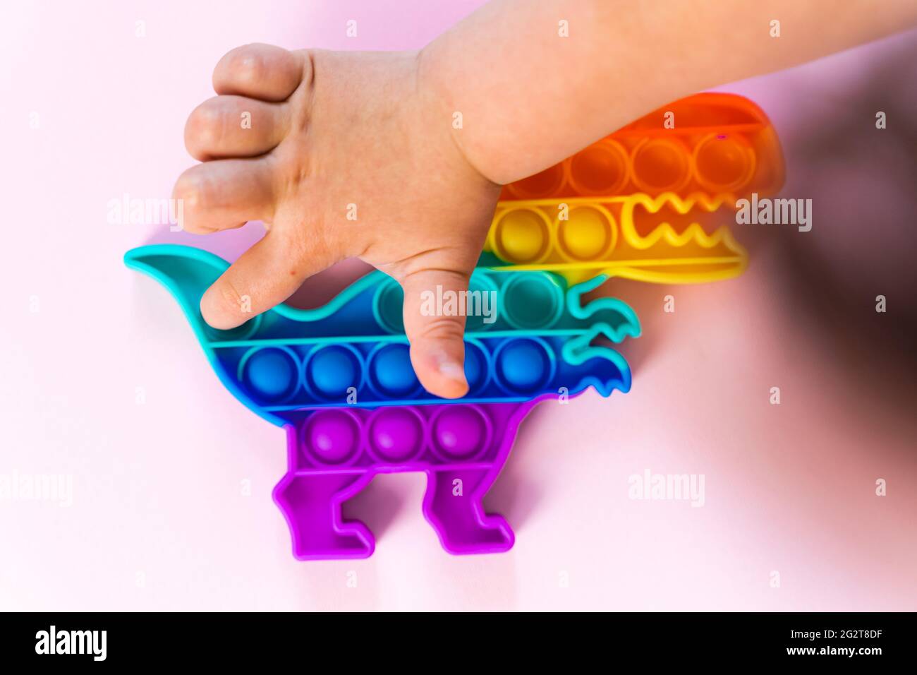 Popit rainbow toy in rainbow colours and dino shape. Trendy bubble pop ...