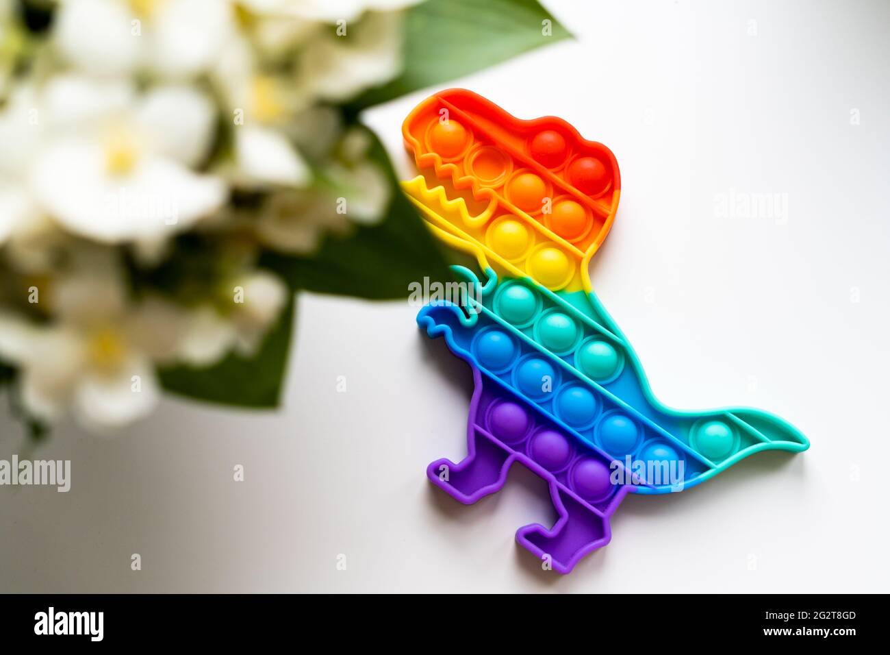 Popit rainbow toy in rainbow colours and dino shape. Trendy bubble pop ...