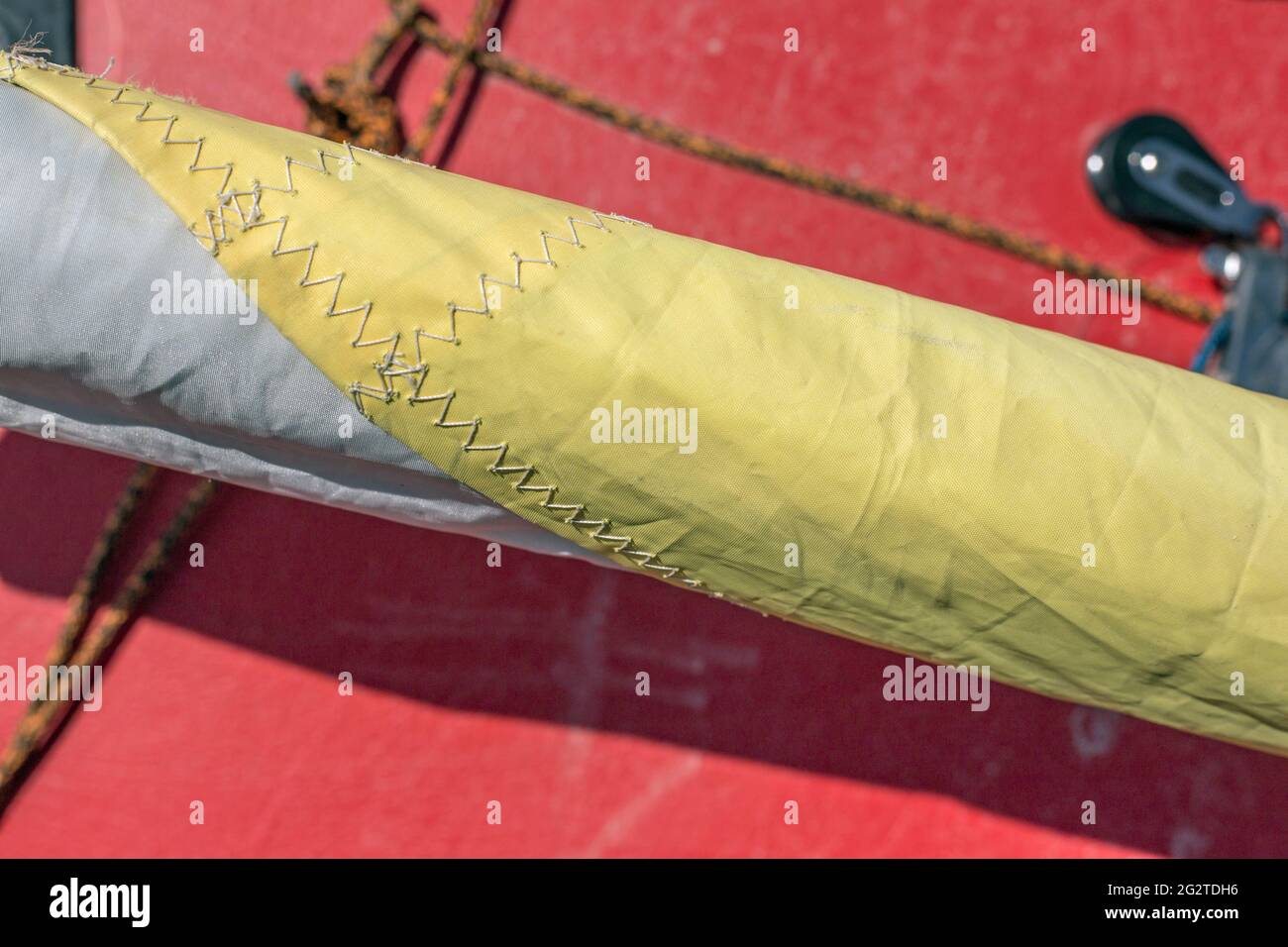 Abstract image of a yellow canvas sail rolled tightly and leaning ...