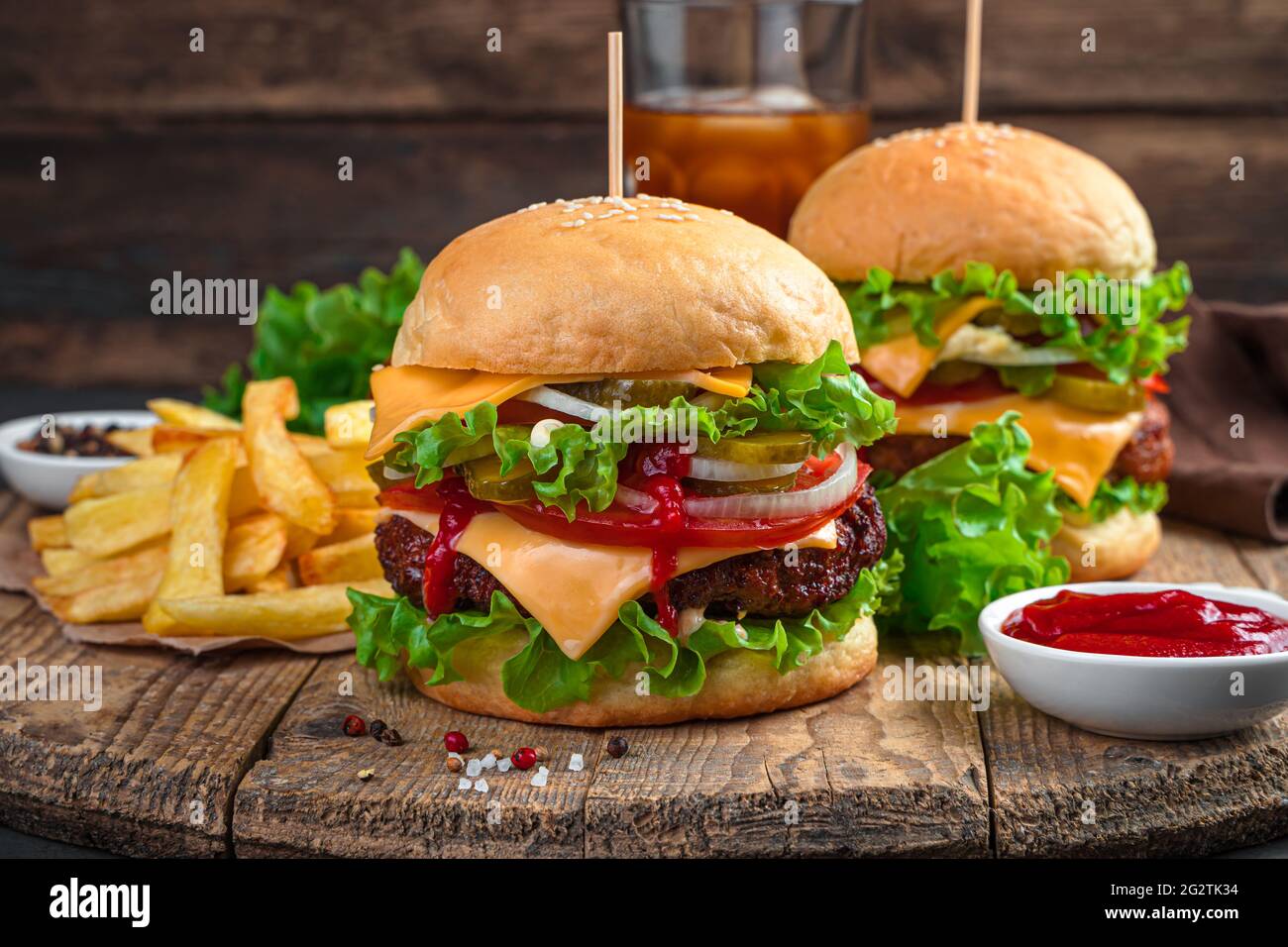Lunch with burgers on a brown background. Two juicy burgers with French ...
