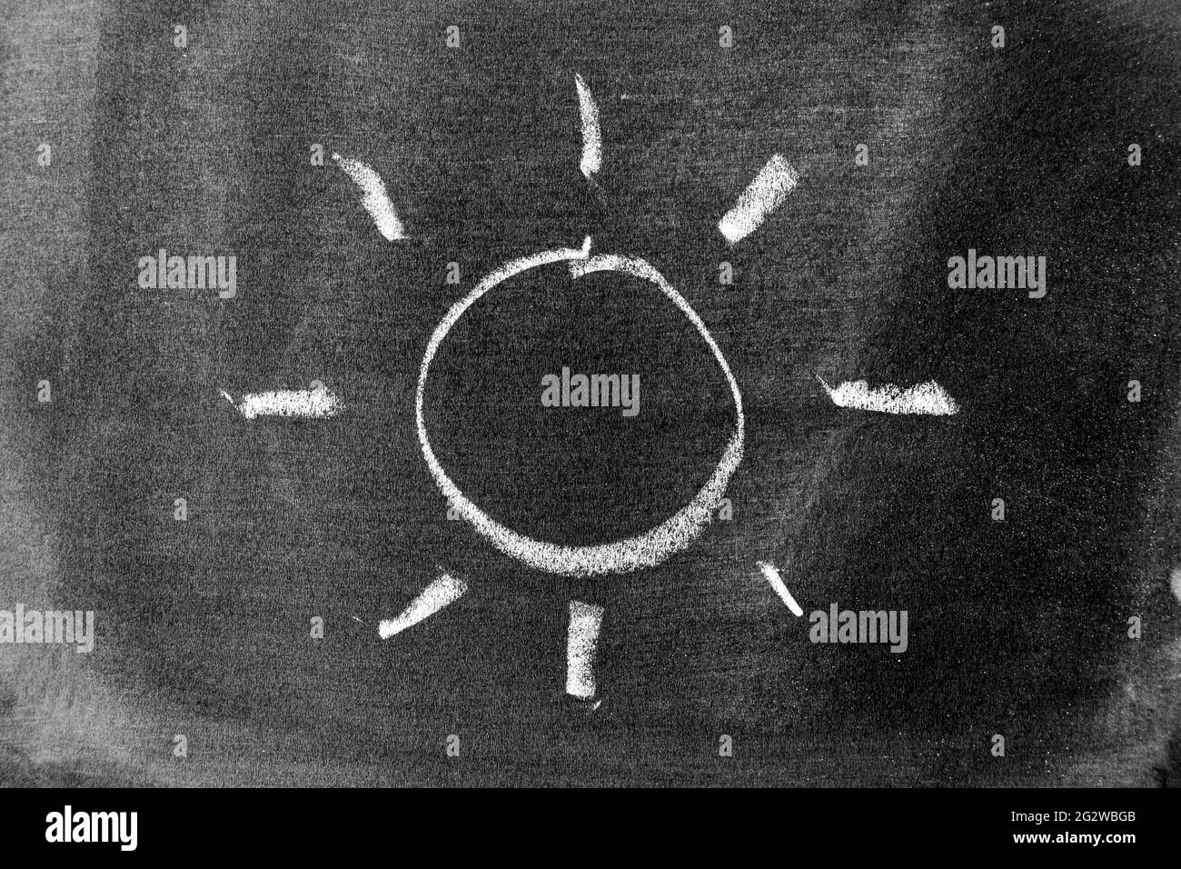 White color chalk hand drawing in sun with ray shape on blackboard or ...