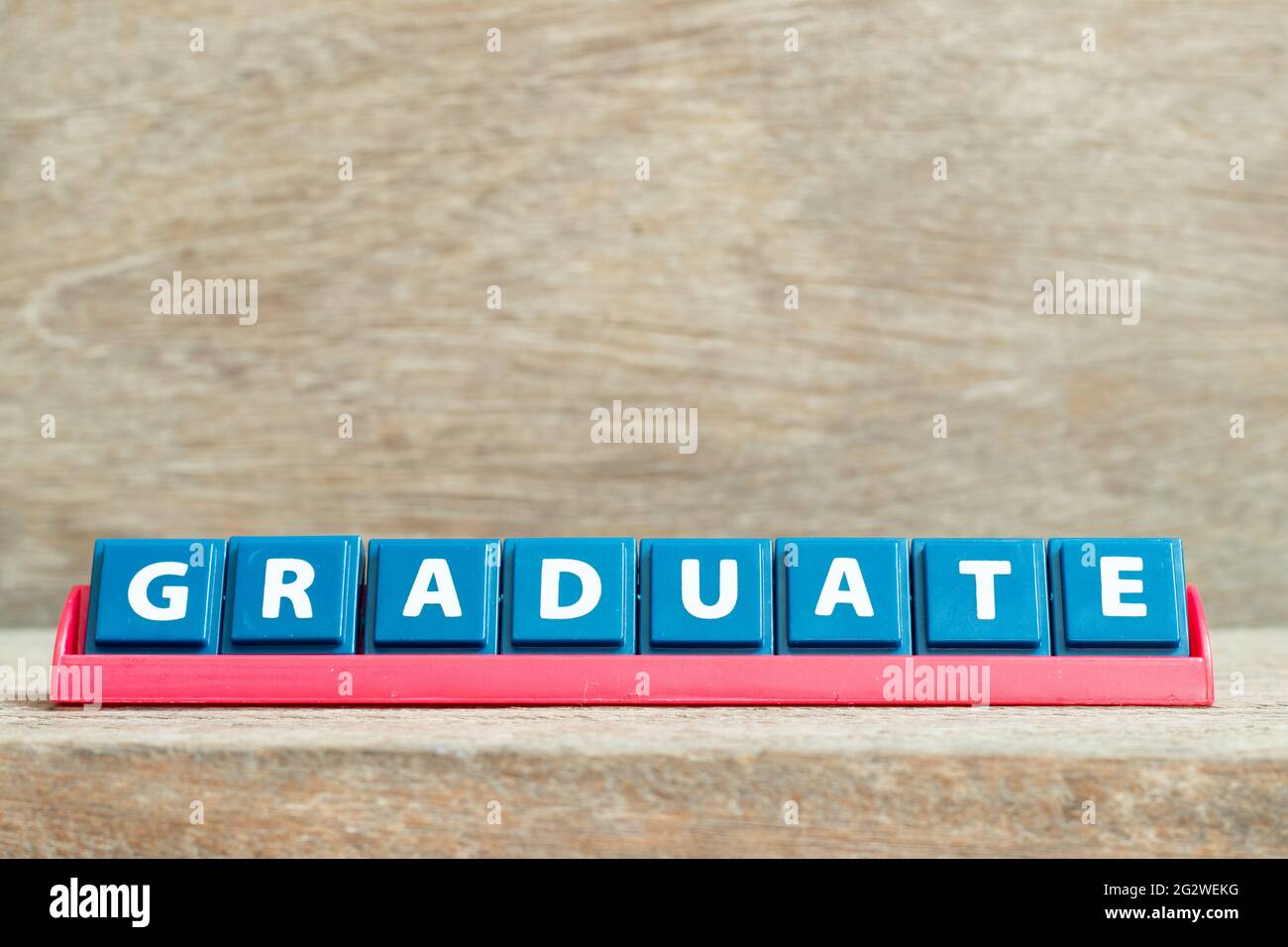 Tile alphabet letter with word graduate in red color rack on wood ...