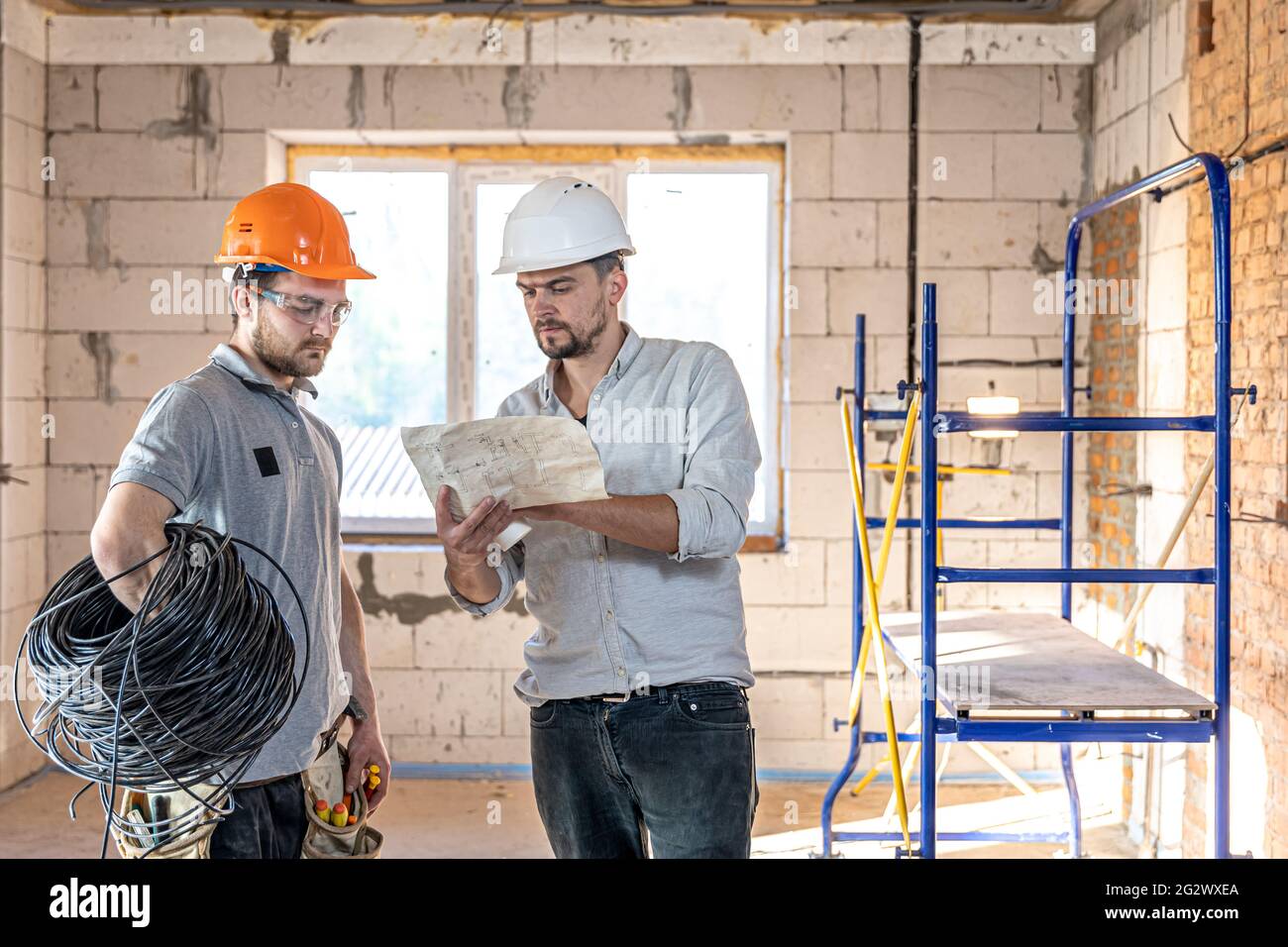 Two builder engineers talking at building site, engineer explaining a ...
