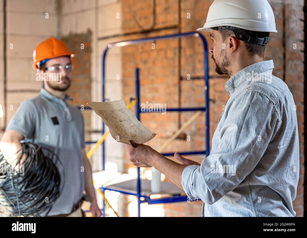 Two builder engineers talking at building site, engineer explaining a ...