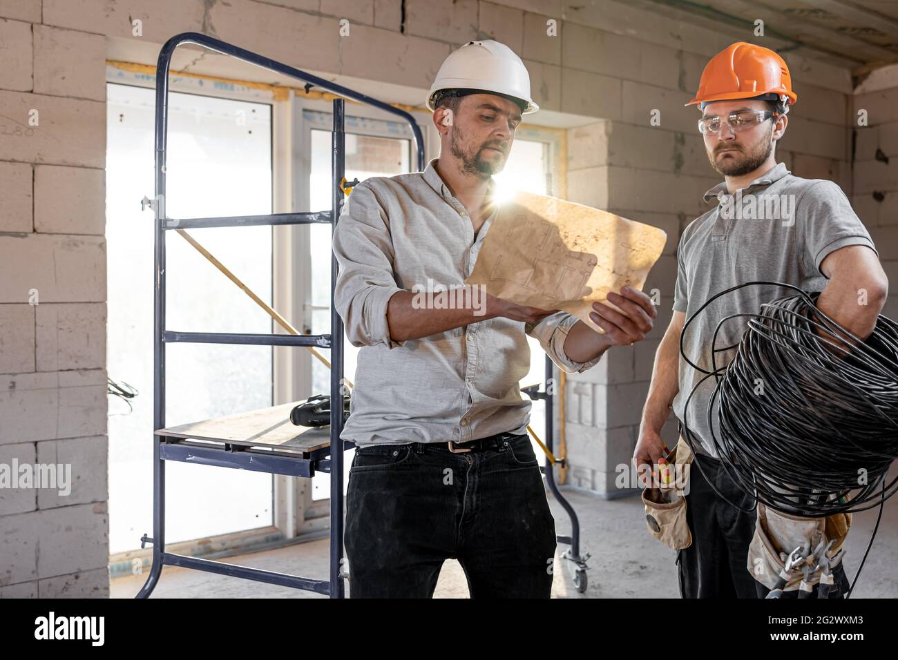 Two builder engineers talking at building site, engineer explaining a ...
