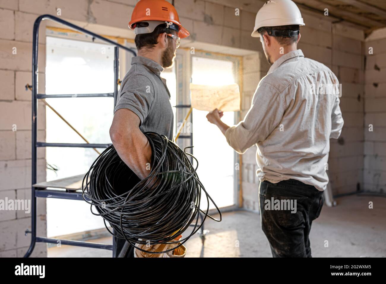 Two builder engineers talking at building site, engineer explaining a ...
