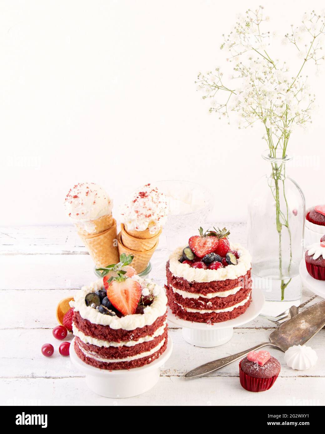 Delicious cake and cupcakes in red on white background. Table setting ...