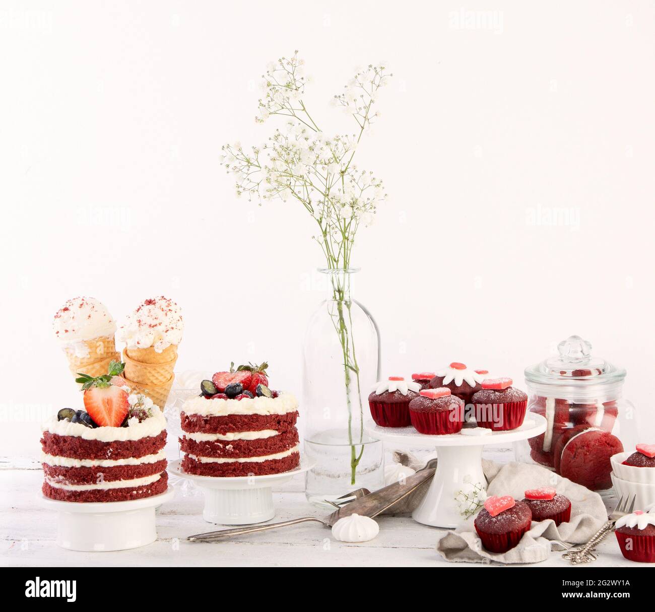 Delicious cake and cupcakes in red on white background. Table setting ...