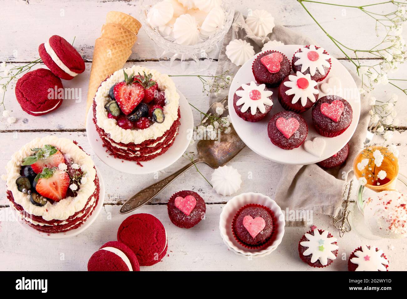 Delicious cake and cupcakes in red on white background. Table setting ...