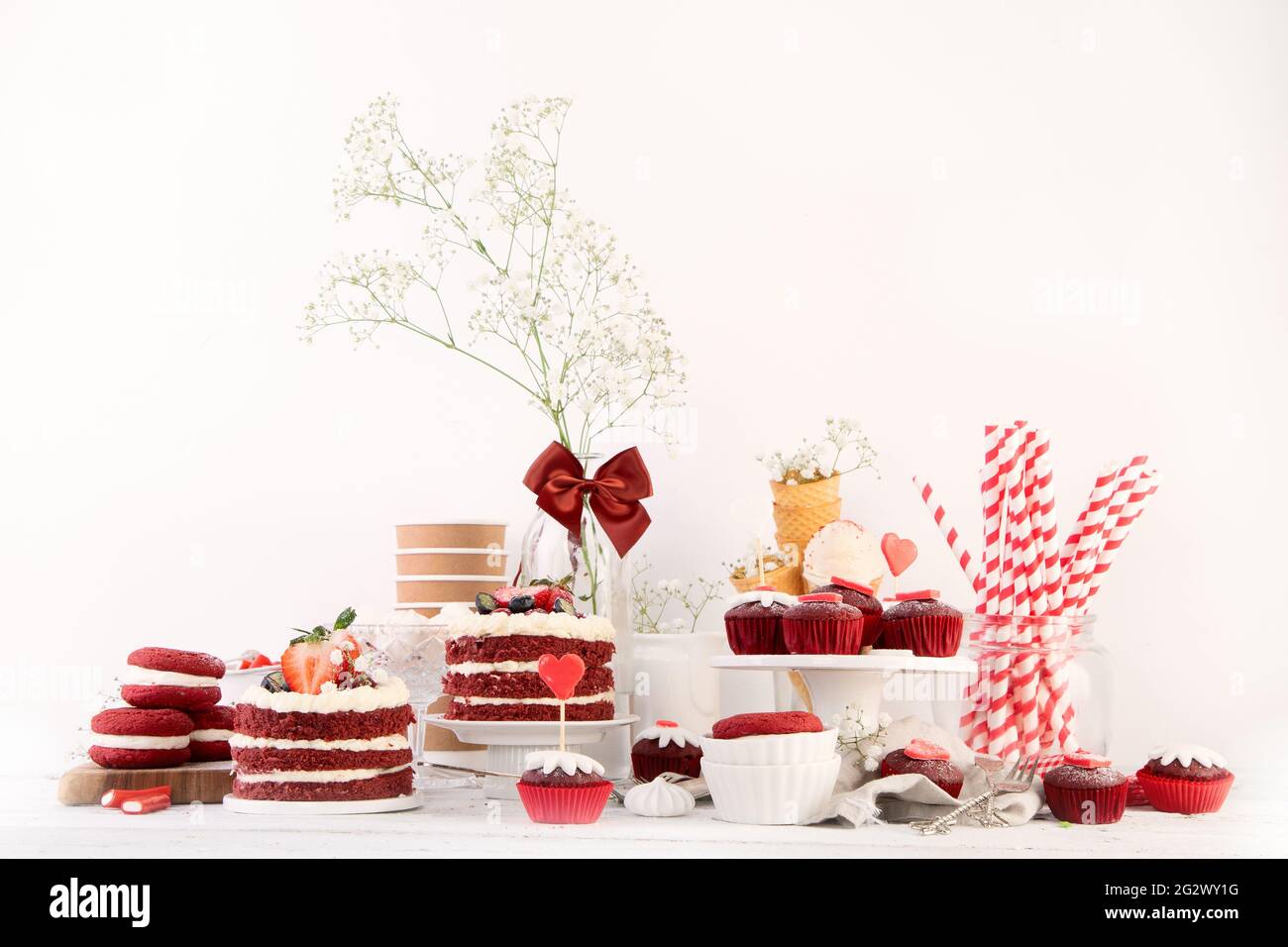 Delicious cake and cupcakes in red on white background. Table setting ...