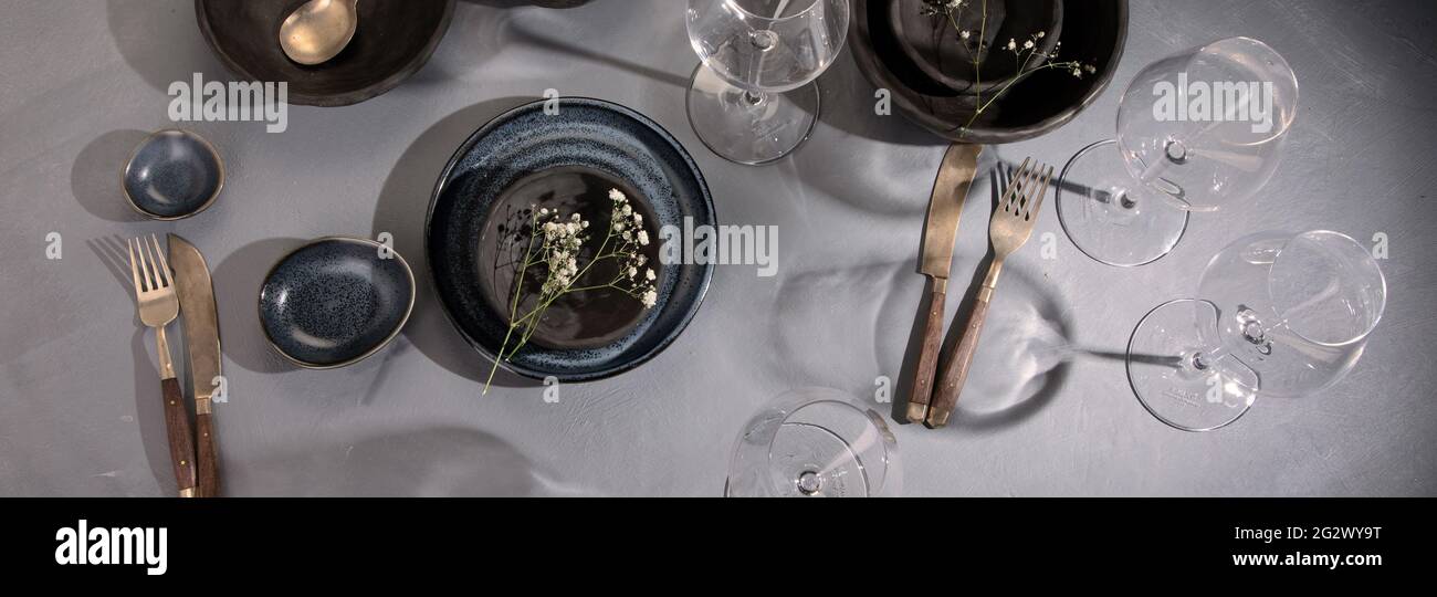 Table setting with a black and blue plates on gray background ...